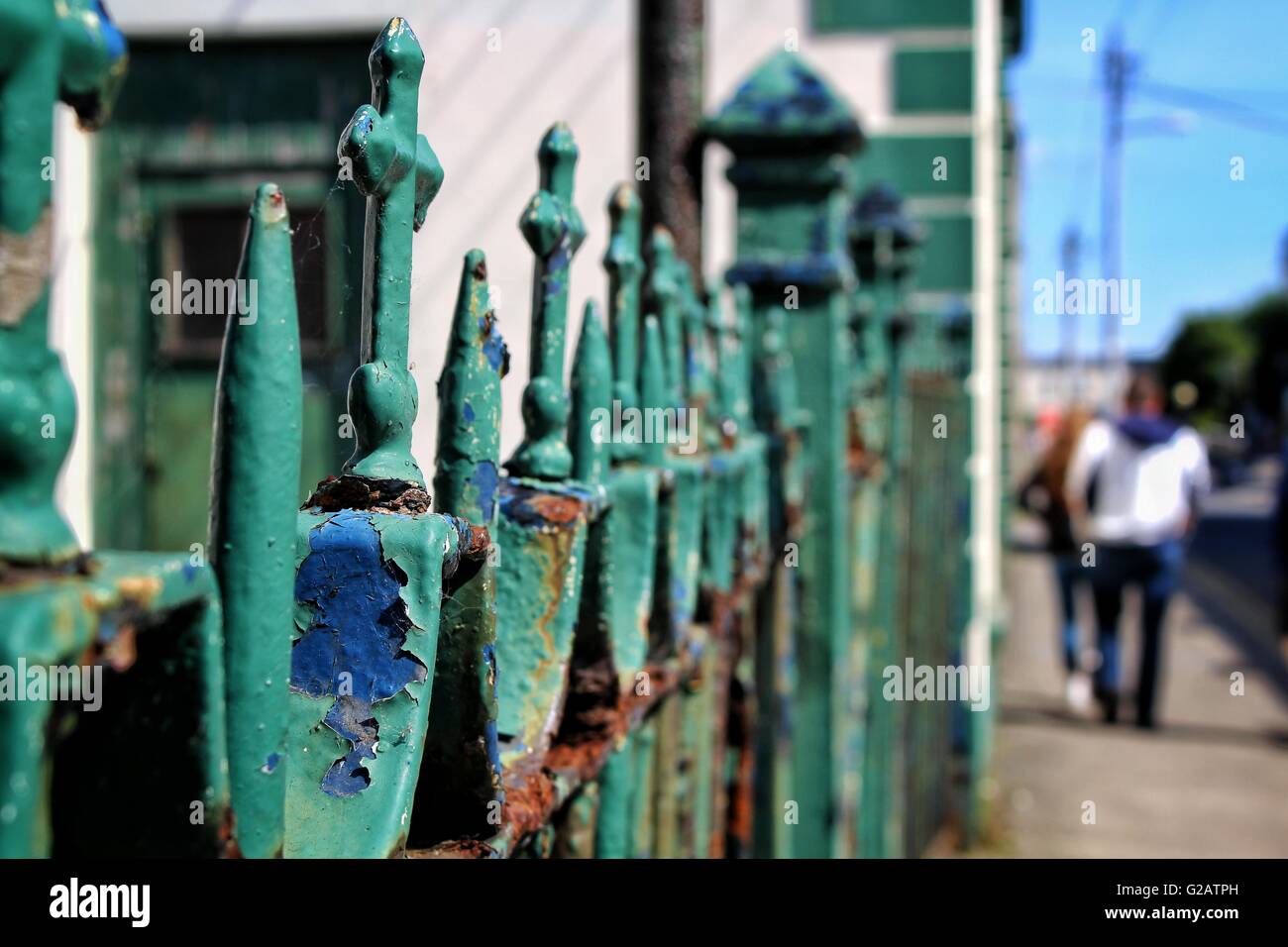 A rusted, decrepit, copper railing on the side of a street with the ...