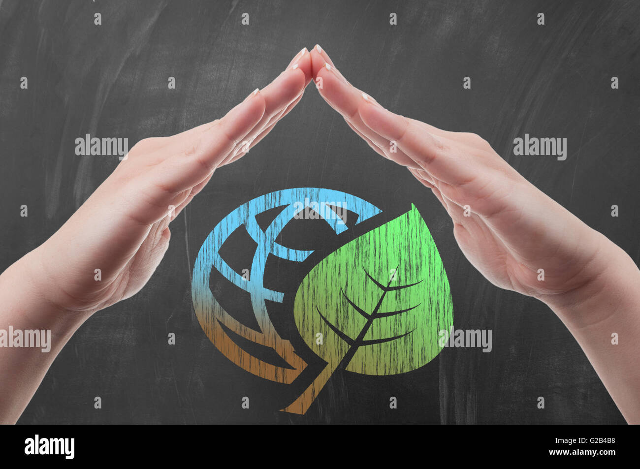 Hand protecting earth globe with green leaf draw on blackboard as ...