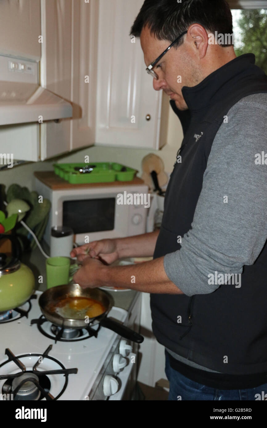 Young man cooking eggs hi-res stock photography and images - Alamy