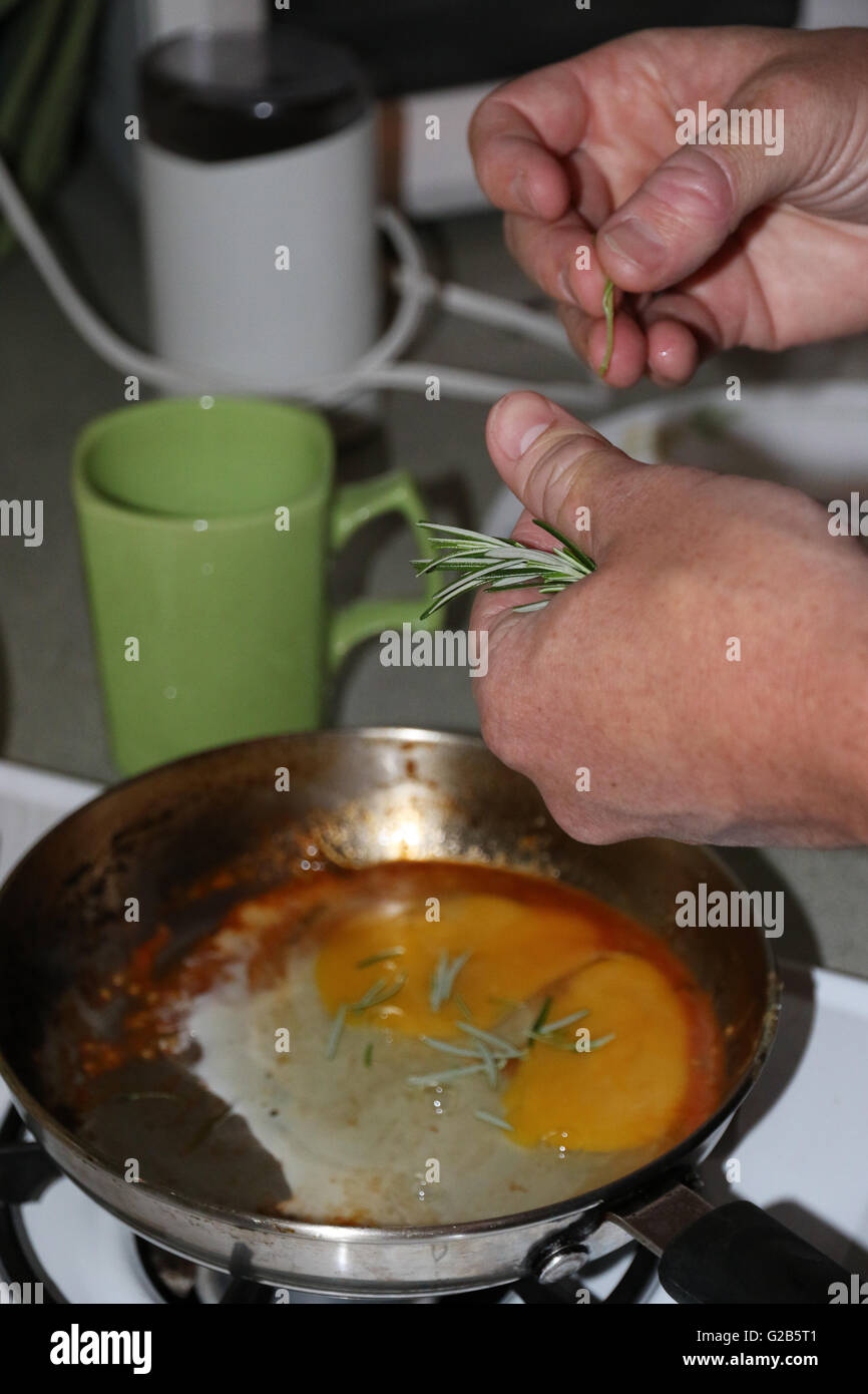 Man cooking eggs with rosemary Stock Photo - Alamy