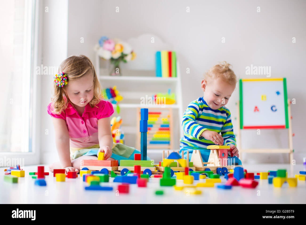 Kids play at day care. Two toddler children build tower of colorful ...