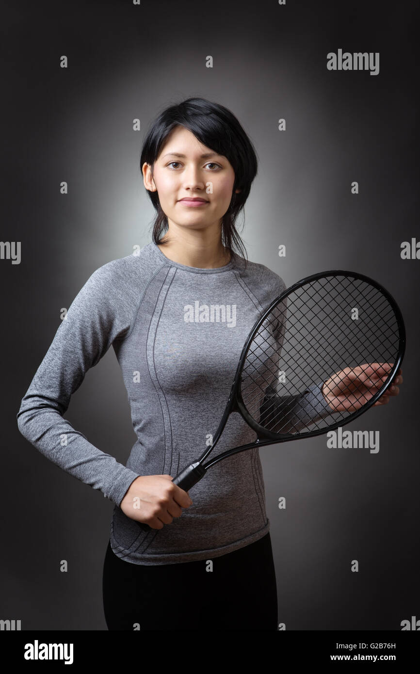 Upper body shot of a slim, pretty, fitness model holding a tennis ...