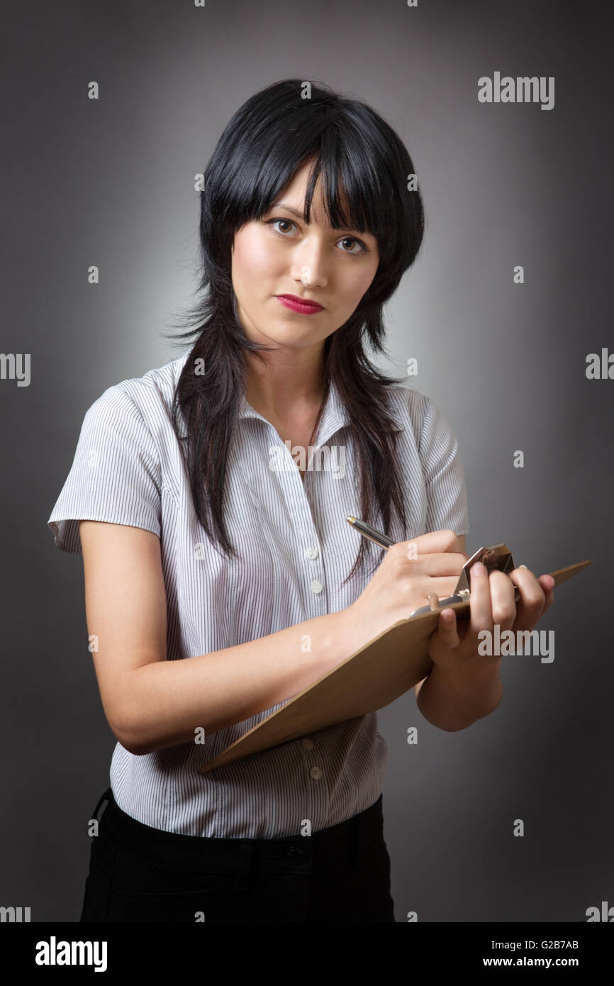 business woman looking at camera, using a clipboard and a pen Stock ...