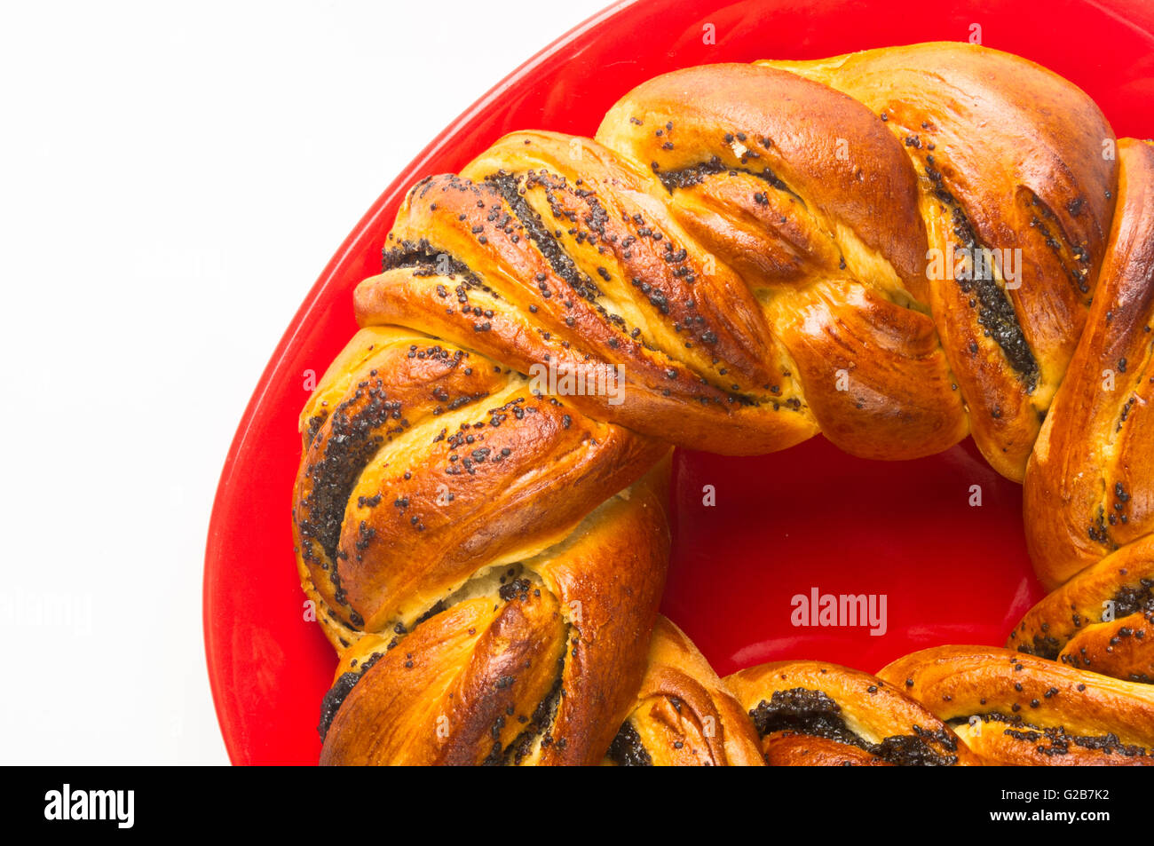 braided poppy seed round loaf in a red plate on white background Stock ...