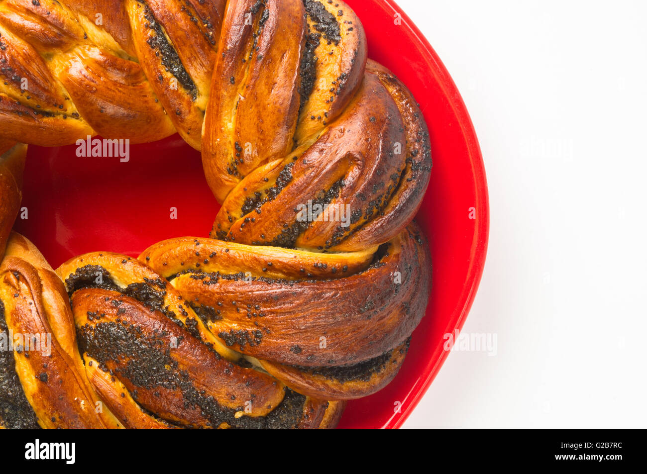 braided poppy seed round loaf in a red plate on white background Stock ...