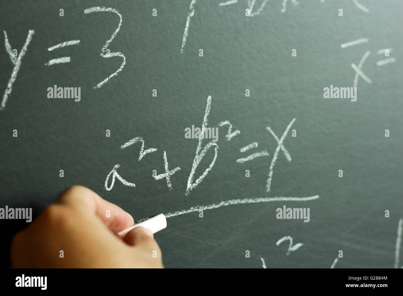 Teacher writing various high school maths formula on chalkboard Stock ...