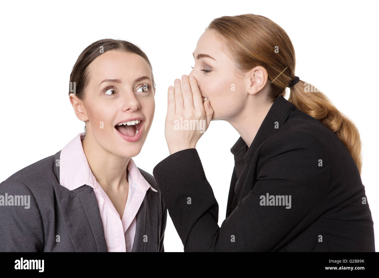 Close up shot of two happy, pretty business women, sharing a secret and ...