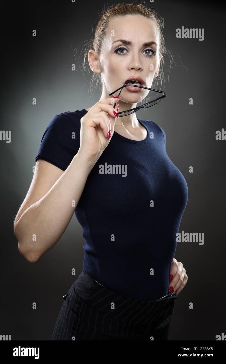 Studio shot of a beautiful business woman holding her glasses raised up ...