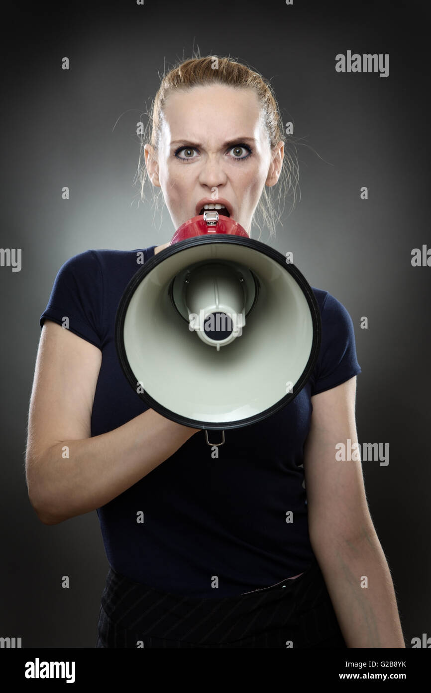 Studio shot of a pretty business model shouting into a megaphone. Shot ...