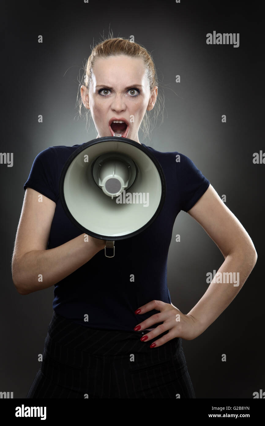 Studio shot of a pretty business model shouting into a megaphone. Shot ...