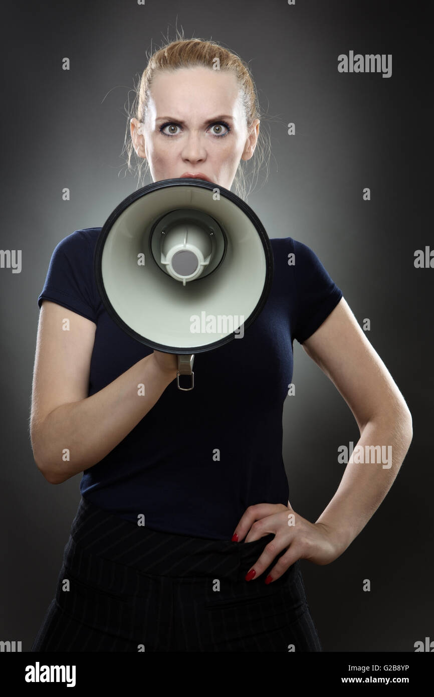 Studio shot of a pretty business model shouting into a megaphone. Shot ...