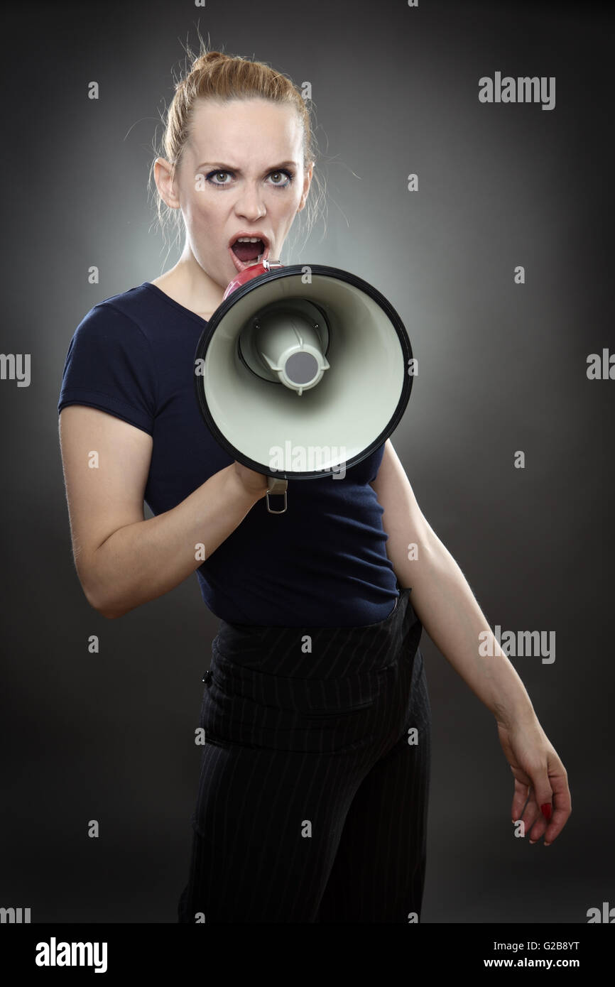 Studio shot of a pretty business model shouting into a megaphone. Shot ...