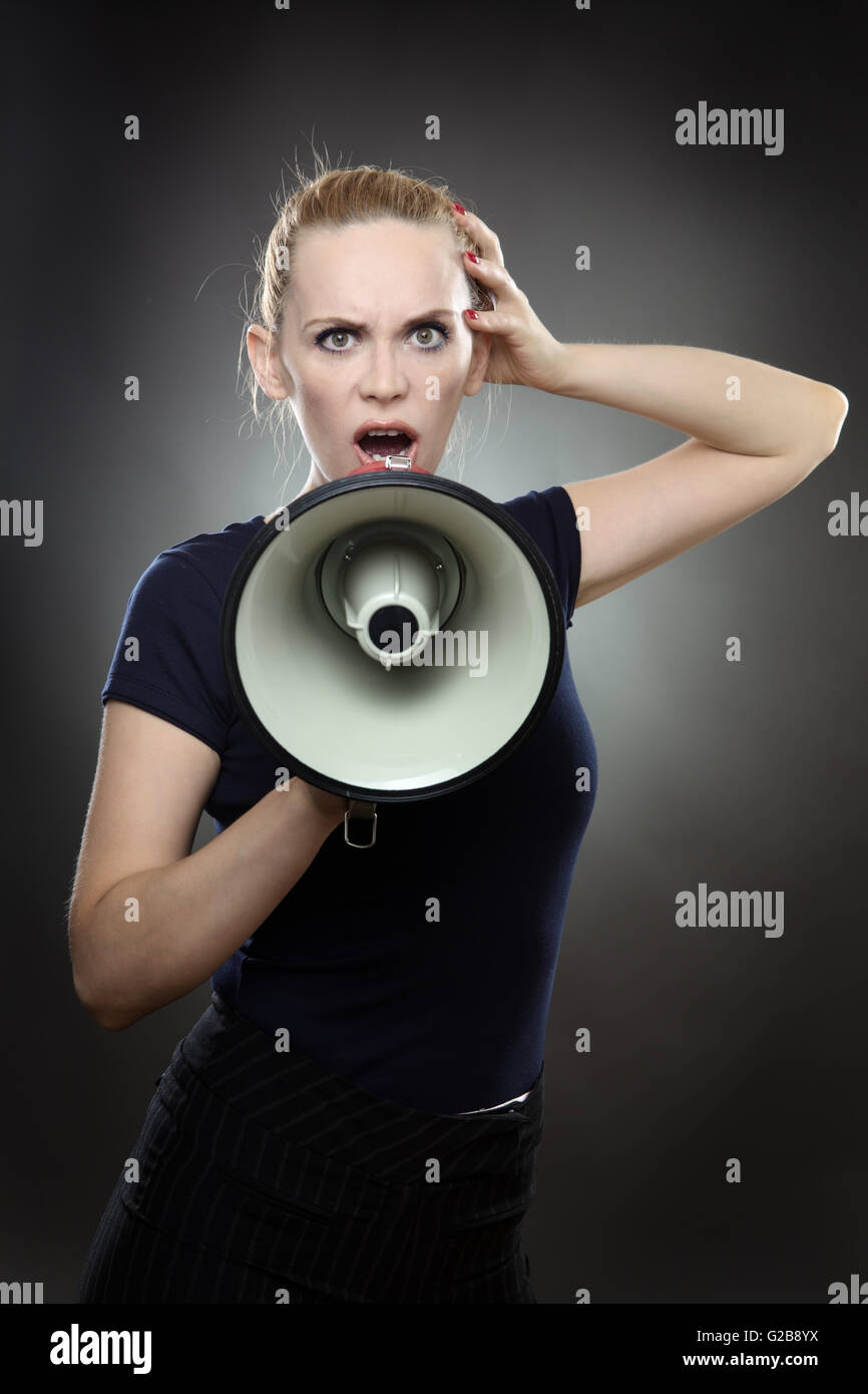 Studio shot of a pretty business model shouting into a megaphone. Shot ...