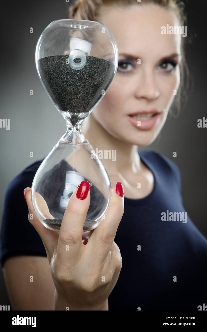 Studio shot of a pretty business model holding a large sandtimer ...