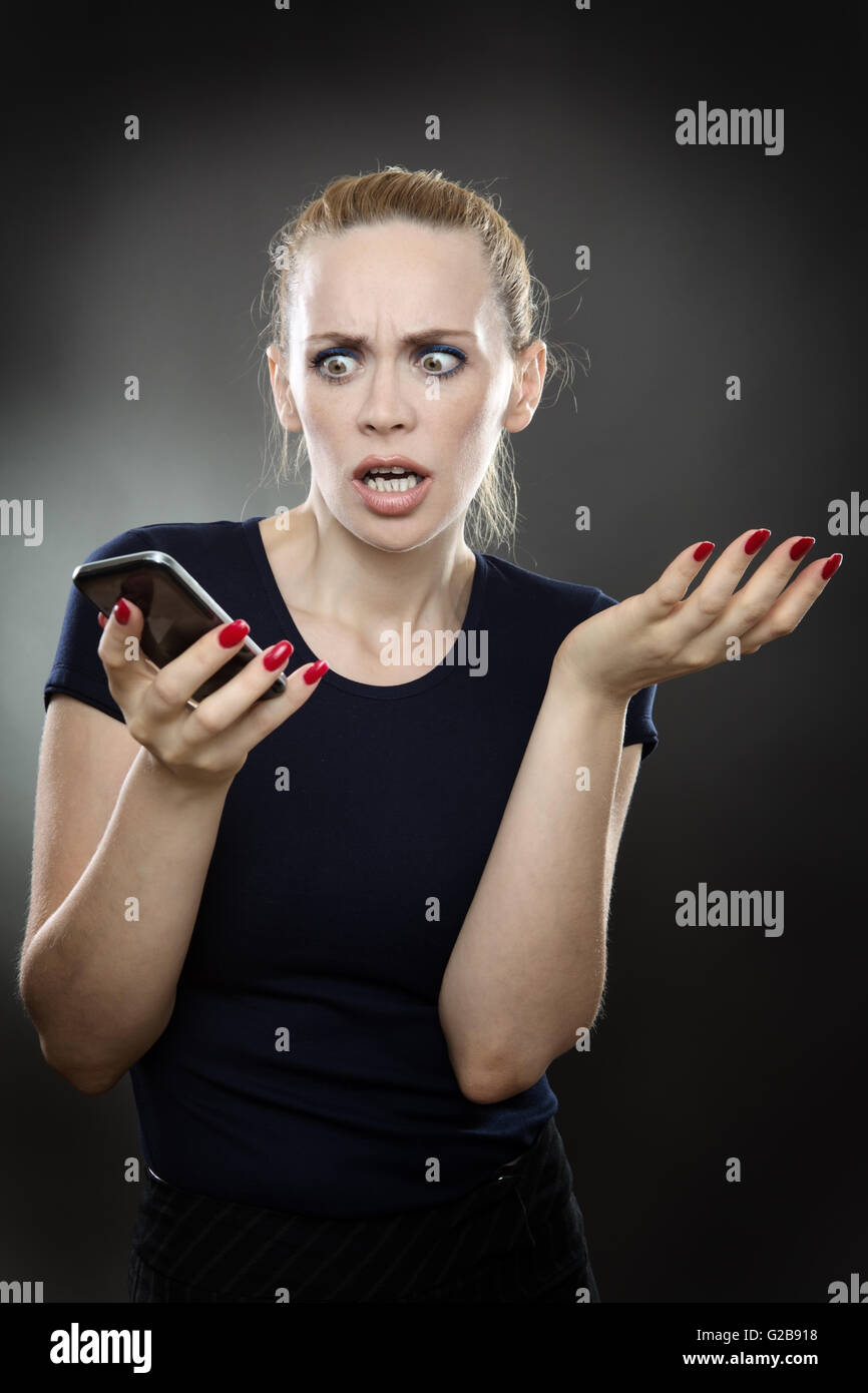 business woman is staring at her mobile phone in disbelief with a ...