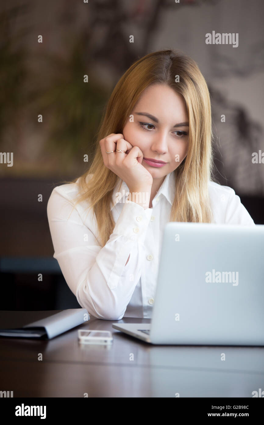 Young beautiful blond caucasian office girl sitting with laptop ...