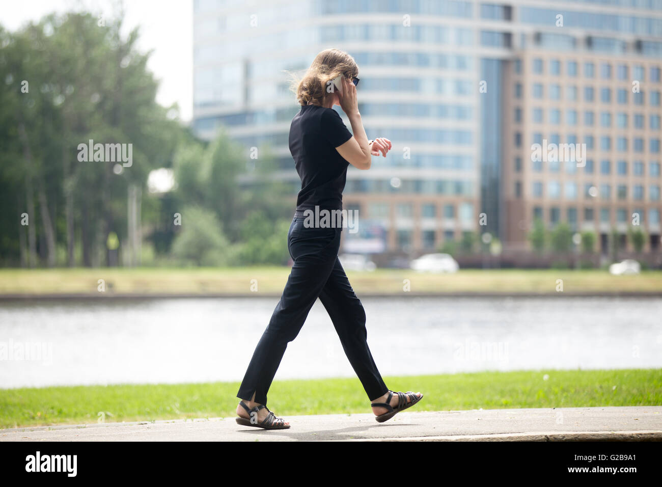 Young business woman running late, walking at fast speed, looking at ...