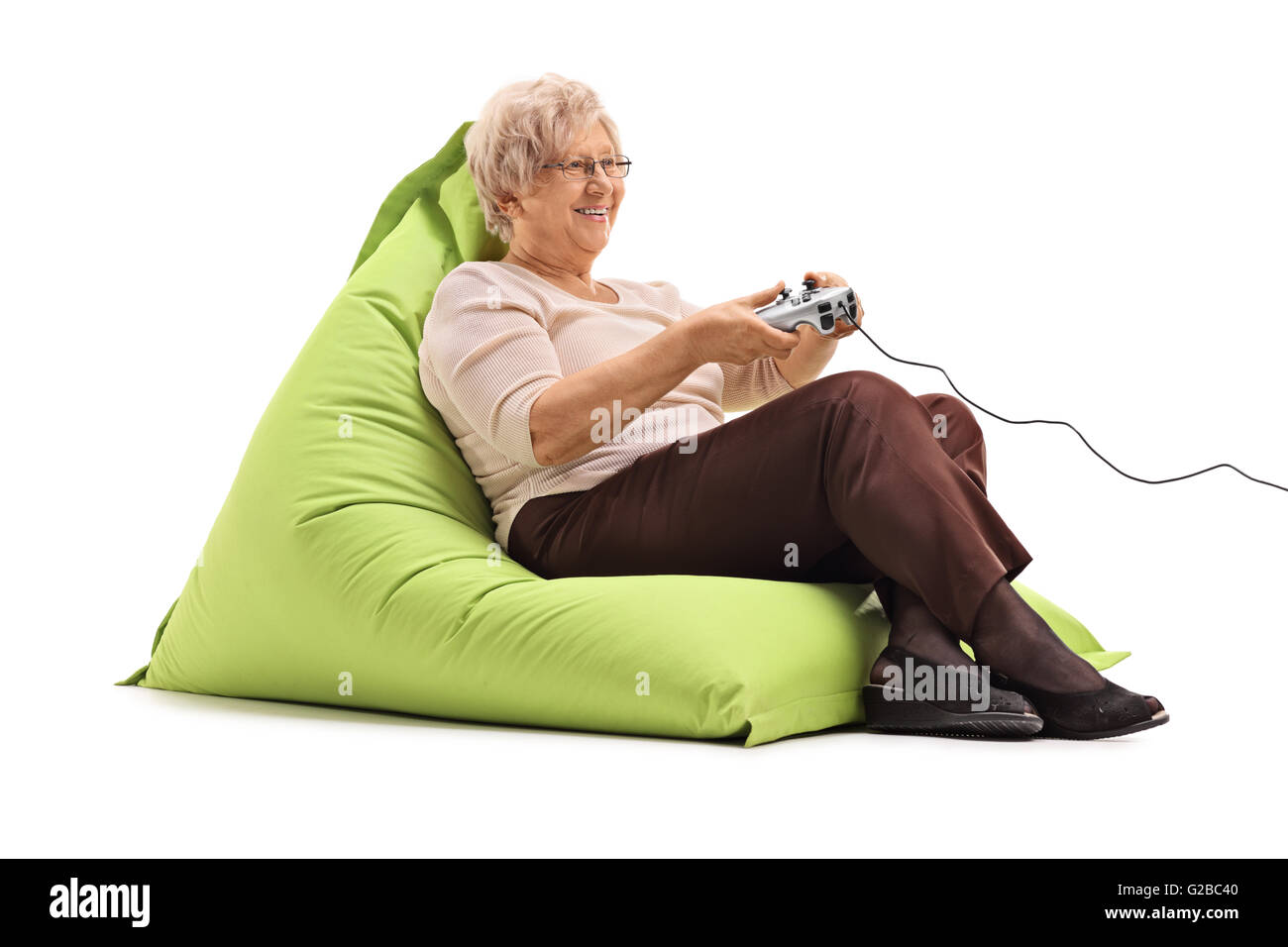 Elderly lady playing video games seated on a comfortable green beanbag ...