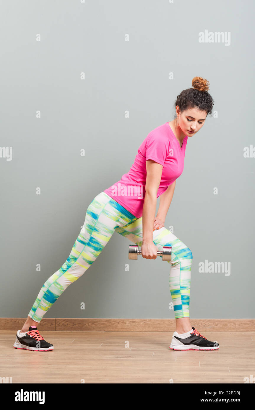 Beautiful woman bending and training with dumbbells and doing sport ...