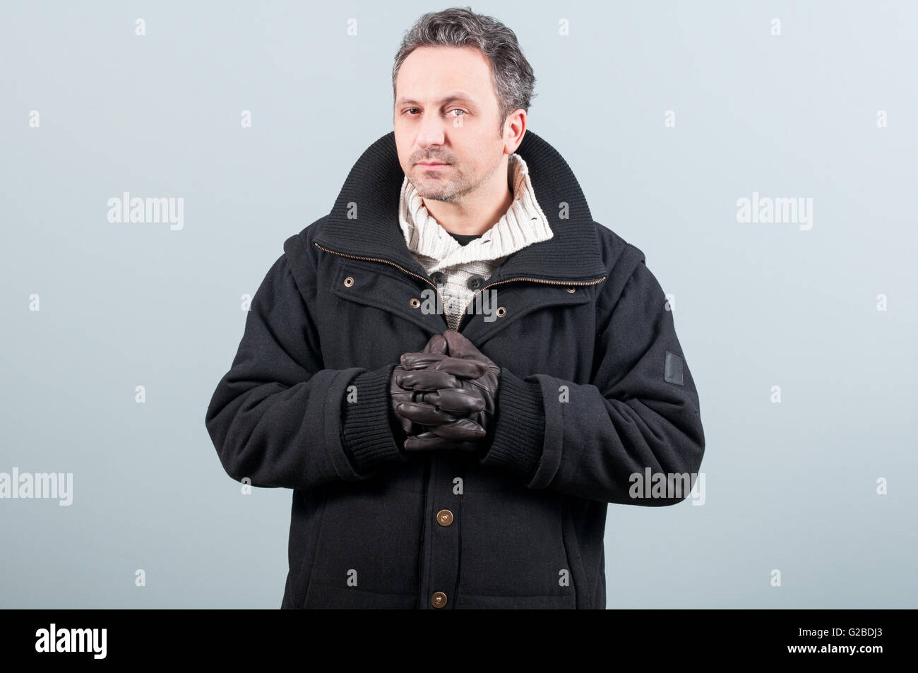 Stylish man wearing winter clothes and leather gloves on gray ...
