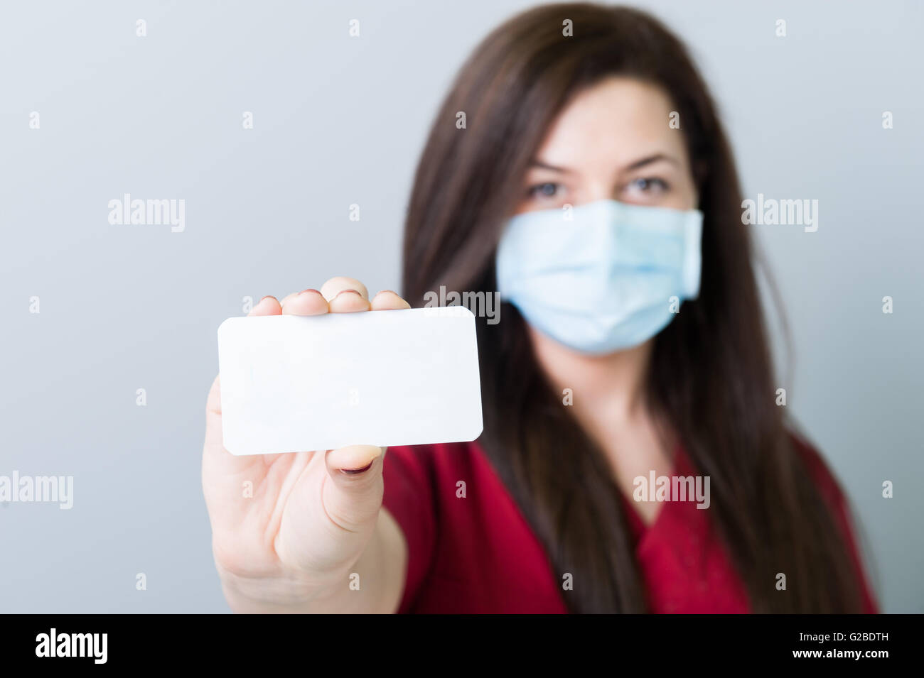 Female doctor holding a blank contact card or paper with copy space and ...