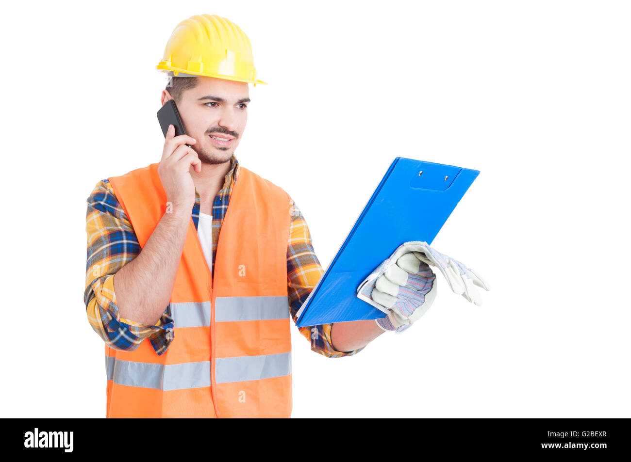 Young engineer wearing helmet with clipboard calling on cellphone as ...