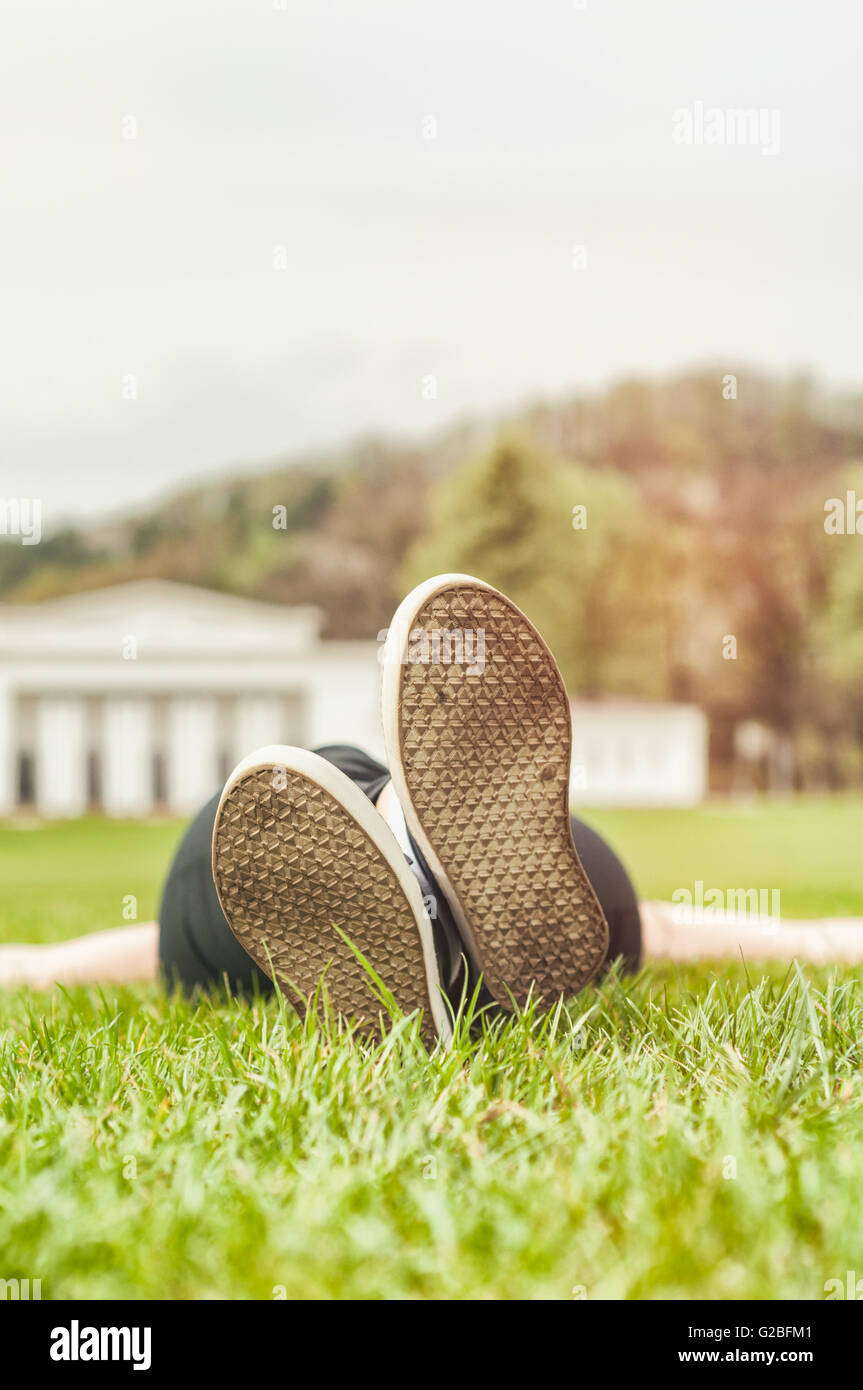 Carefree concept with woman legs lying crosswise on green grass and ...