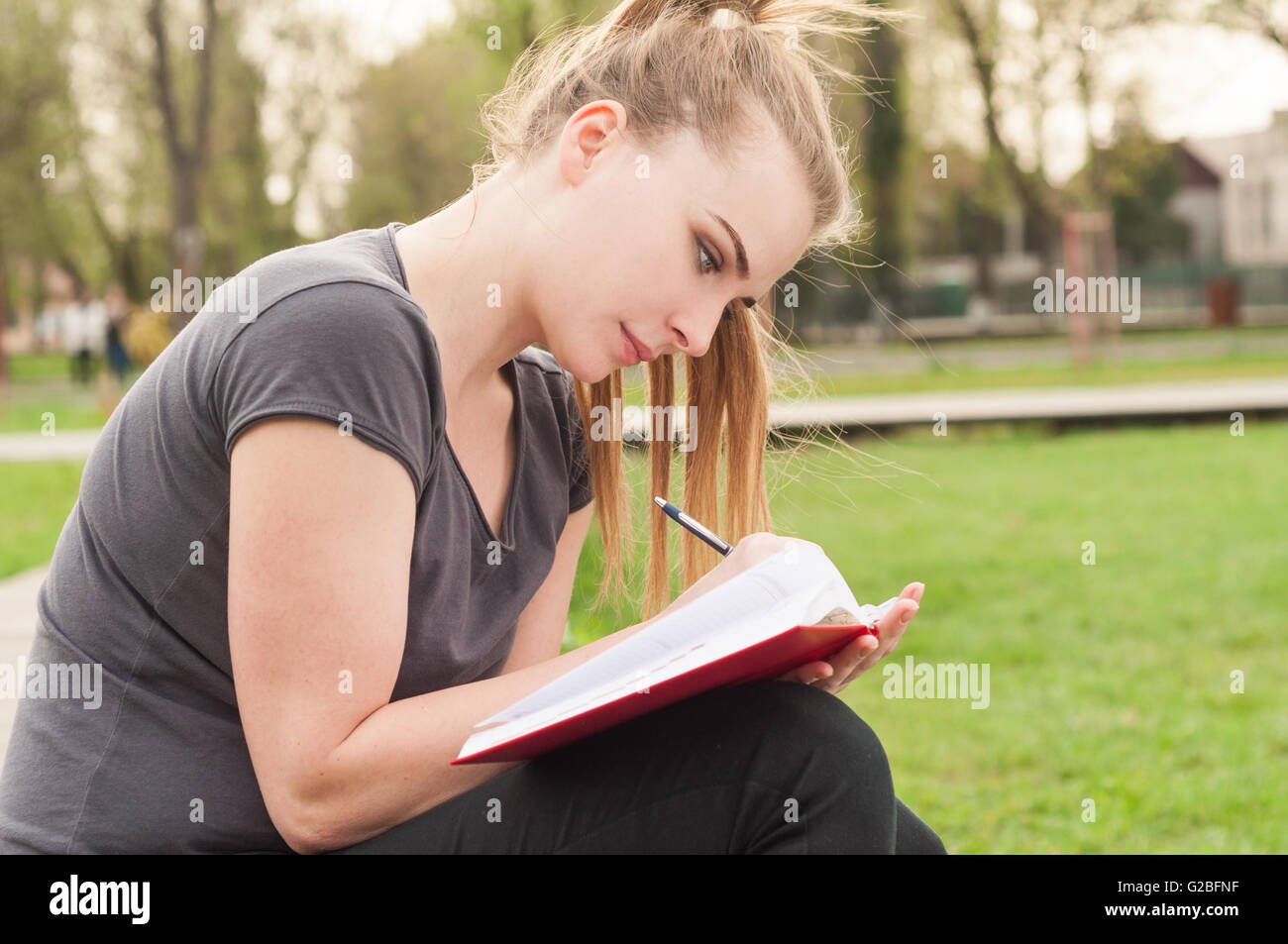 Attractive woman sitting outdoor and writes in her personal journal ...
