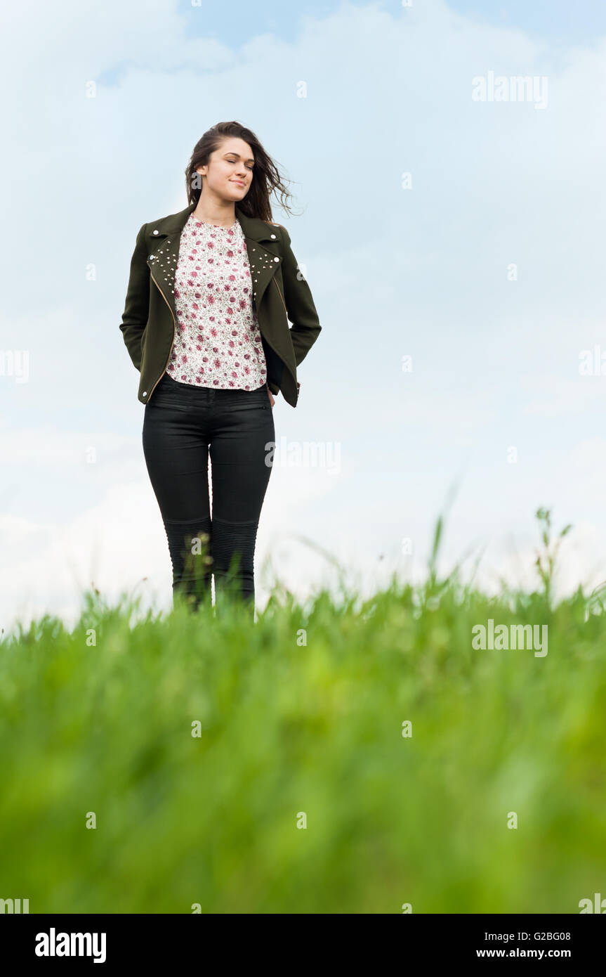 Springtime relaxation with young girl sitting outside on green field ...