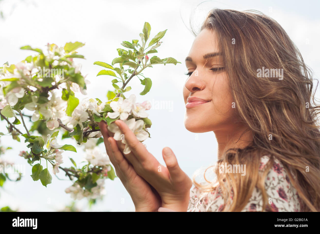 Spring beauty girl enjoying nature and sunshine in the blooming garden ...
