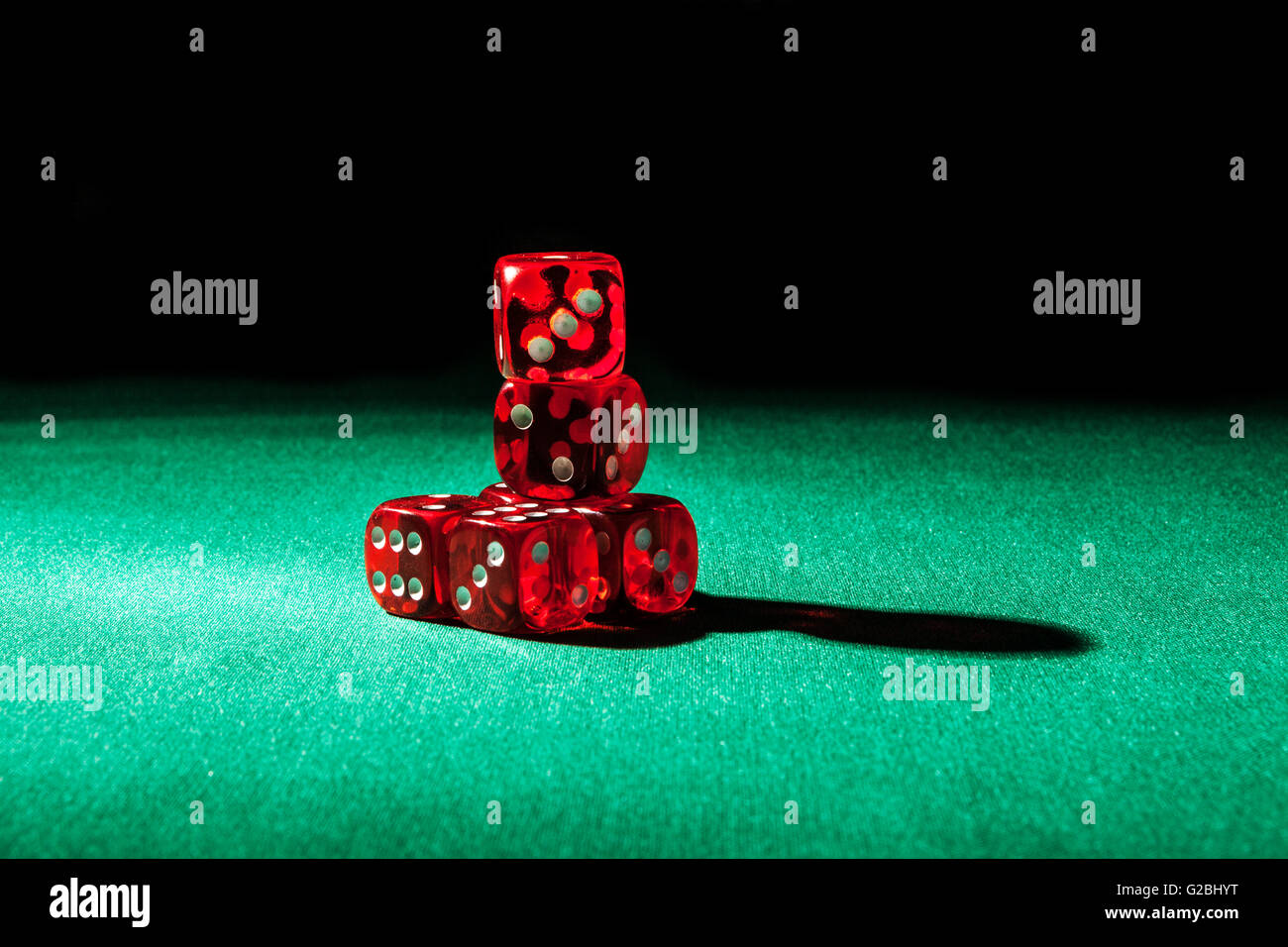 Red dice on green and black background Stock Photo - Alamy