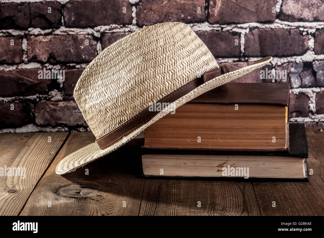 Hat and books on brown wood table Stock Photo - Alamy