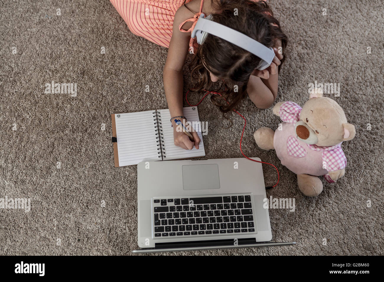 Girl sitting on floor with a notebook and a laptop Stock Photo - Alamy