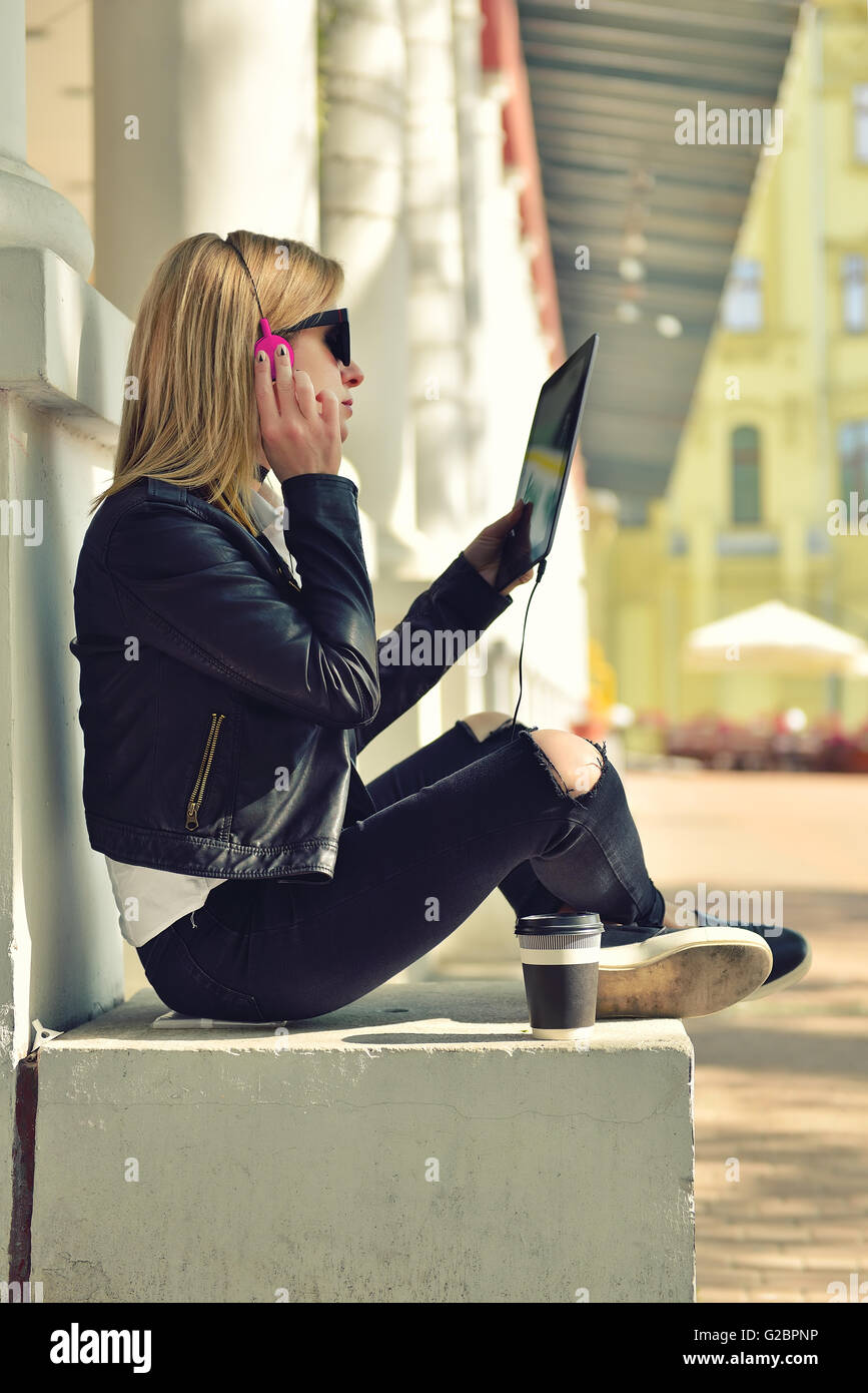 girl sitting with tablet and listening to music, side view Stock Photo ...