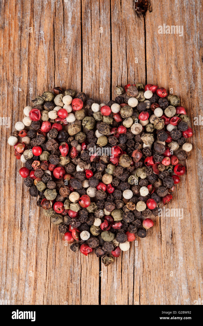Color pepper mixed spices heart shaped on old wood background Stock ...