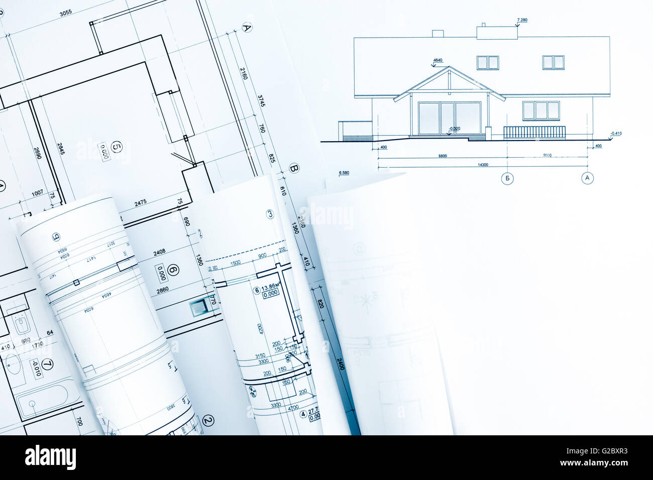 rolls of architectural blueprints and home plan drawings on worktable ...