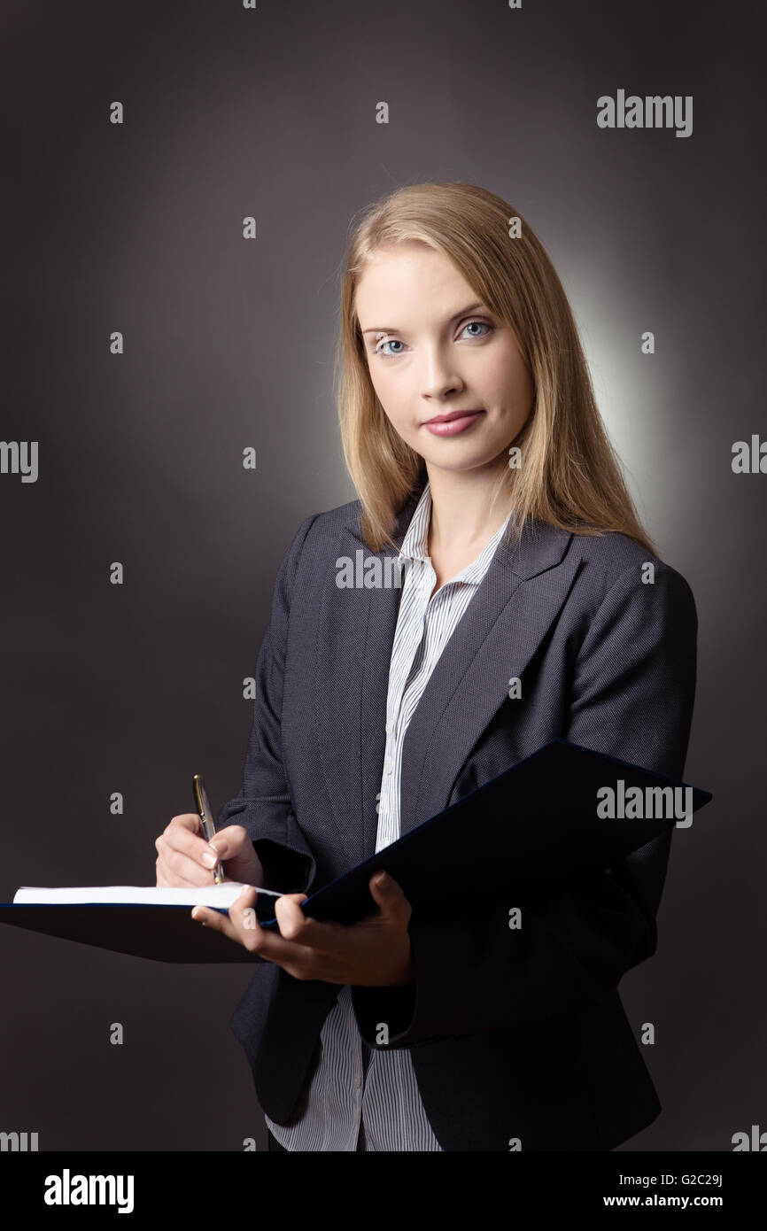 Upper body shot of a smiling business model, holding a book with a pen ...