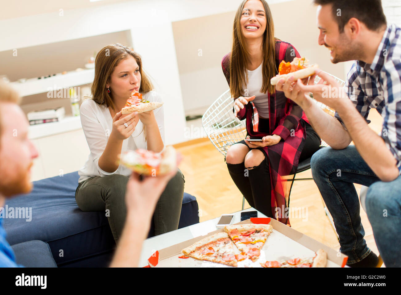 Group of friends eating pizza together at home Stock Photo - Alamy
