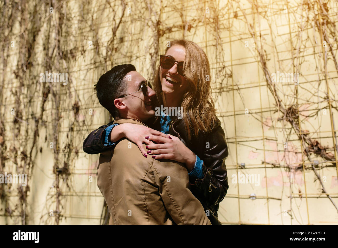 handsome guy and pretty girl posing on a background of a wall overgrown ...
