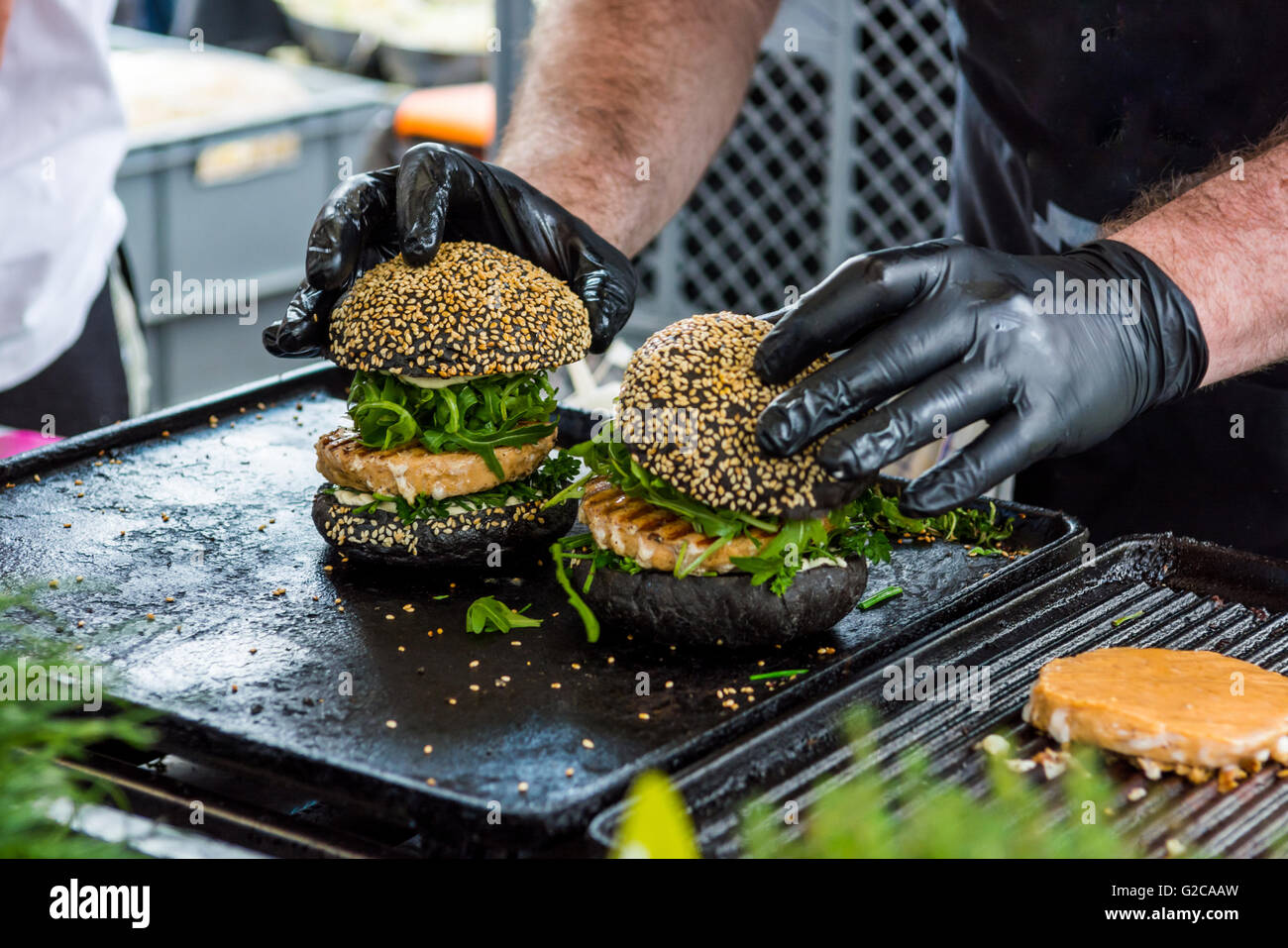 Chef preparing tasty burgers at outdoor stand Stock Photo - Alamy