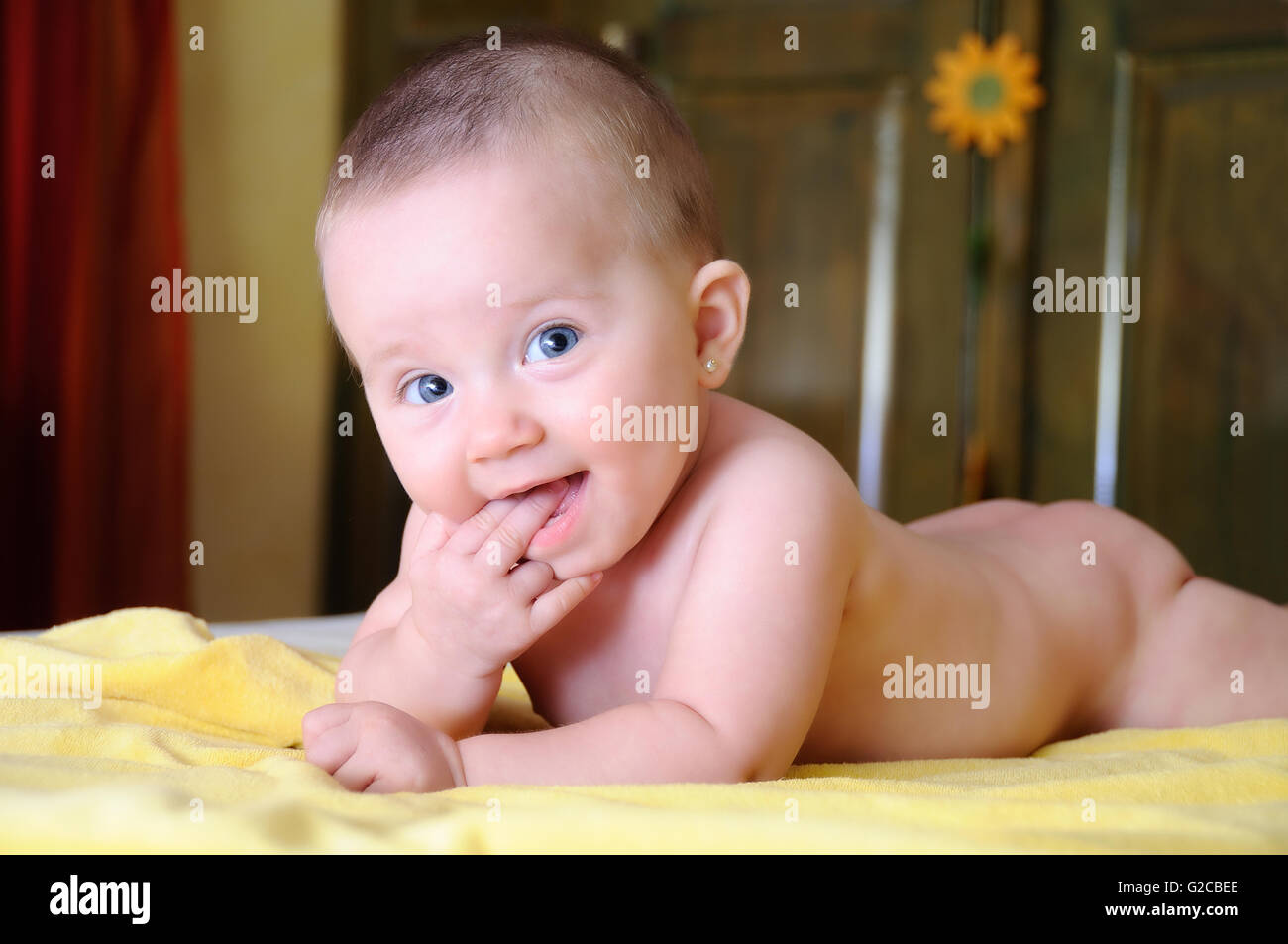 Female Baby bites the hand on a yellow towel on the bed Stock Photo - Alamy