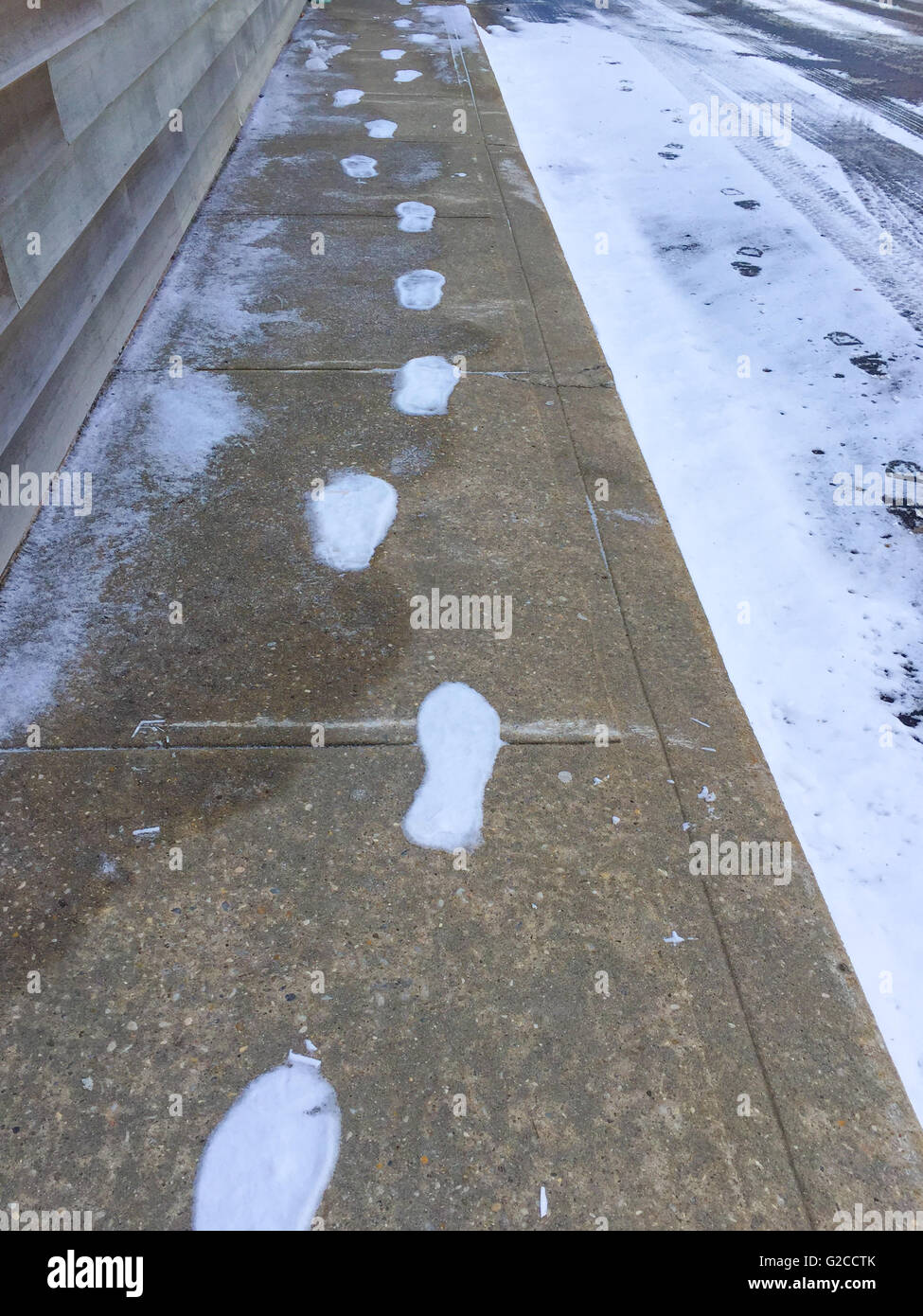 winterscape consisting of frozen foot steps on a cold concrete sidewalk ...