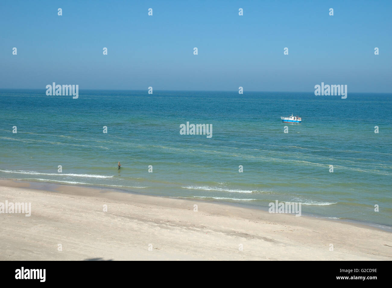 Beach, sea, fisherman and small fishing vessel Stock Photo - Alamy