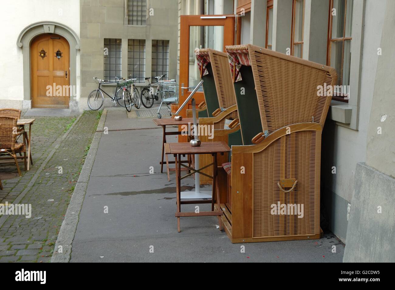 Tables and wicker seats on street at small restaurant Stock Photo - Alamy