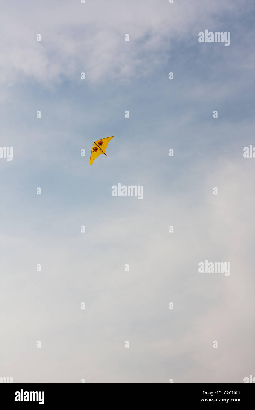 An yellow kite being flown in the wind against blue sky Stock Photo - Alamy
