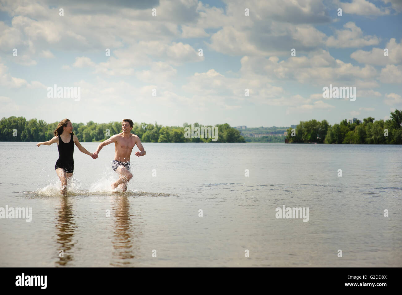 Couple in love. Young couple running through shallow water towards ...