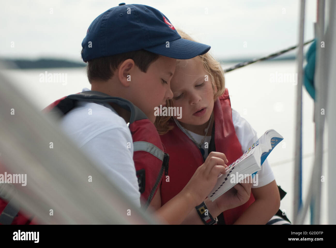 Boy and Girl Looking at Book of Maps on Boat Stock Photo - Alamy