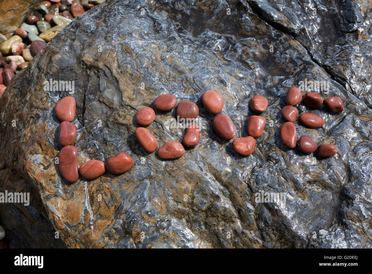 Love Written in Red Stones on a Grey Rock Stock Photo - Alamy