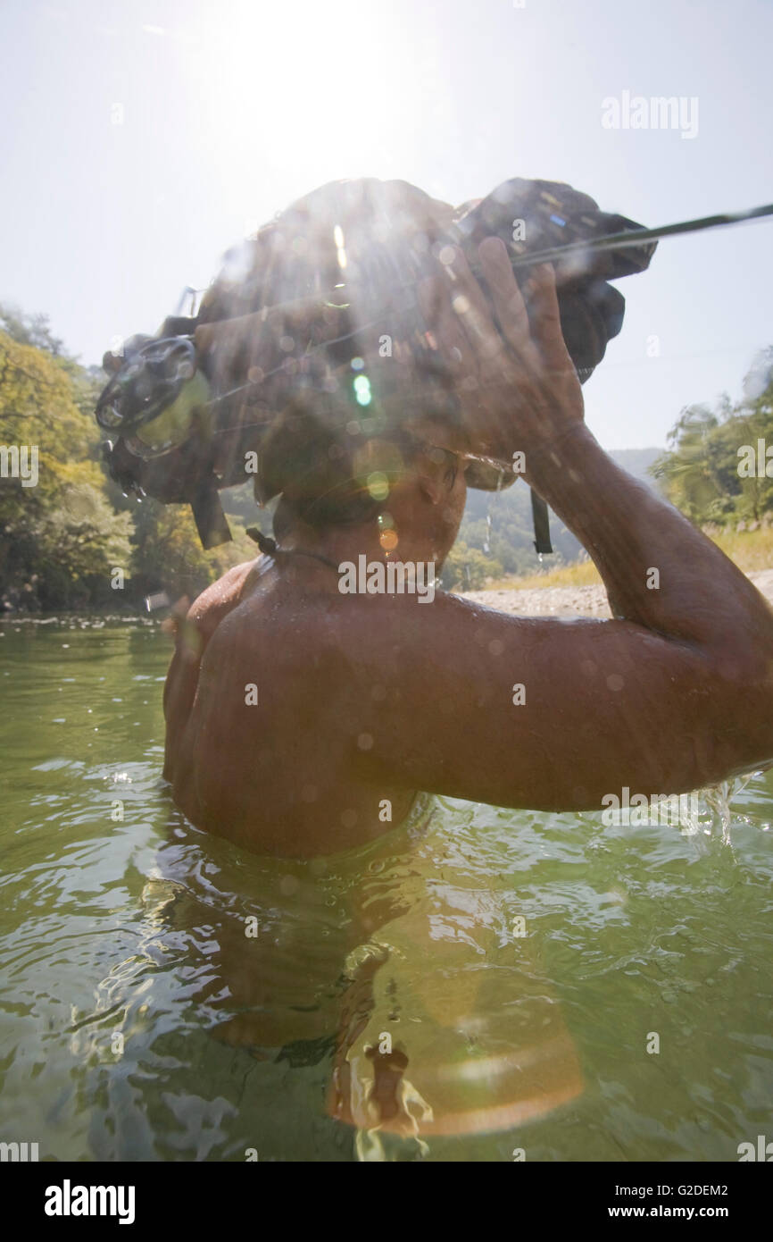 Man in River Carrying Backpack Over Head Stock Photo - Alamy