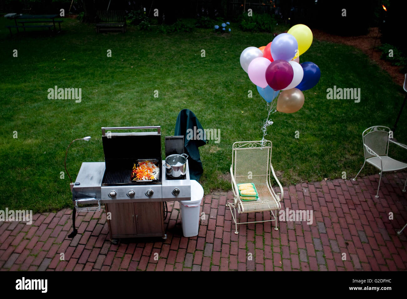 Gas Grill and Helium Balloons Tied to Chair on Brick Patio, High Angle ...
